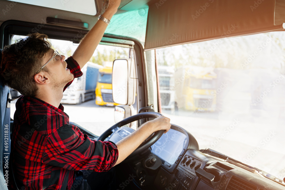 Young truck driver activating tachometer , sitting in truck cabin ...