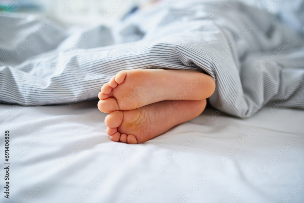 Little child's feet in bed covered with blanket Stock Photo | Adobe Stock