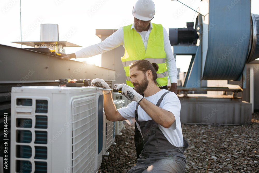 Skilled caucasian repairman fixing air conditioner with screwdriver ...