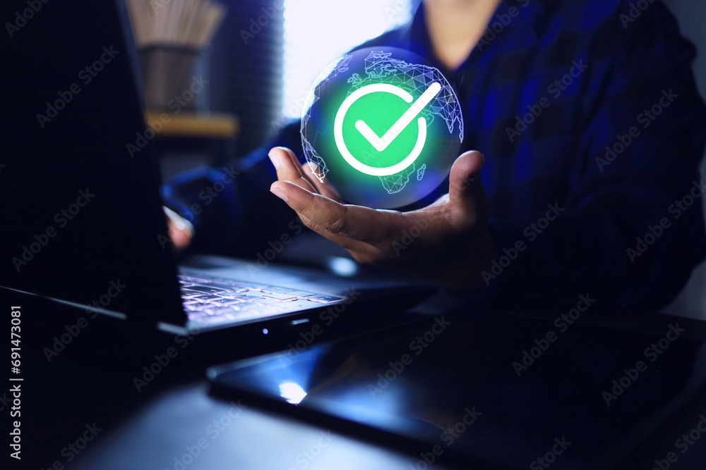 Hand holding globe and correct green checkmark while working on laptop ...