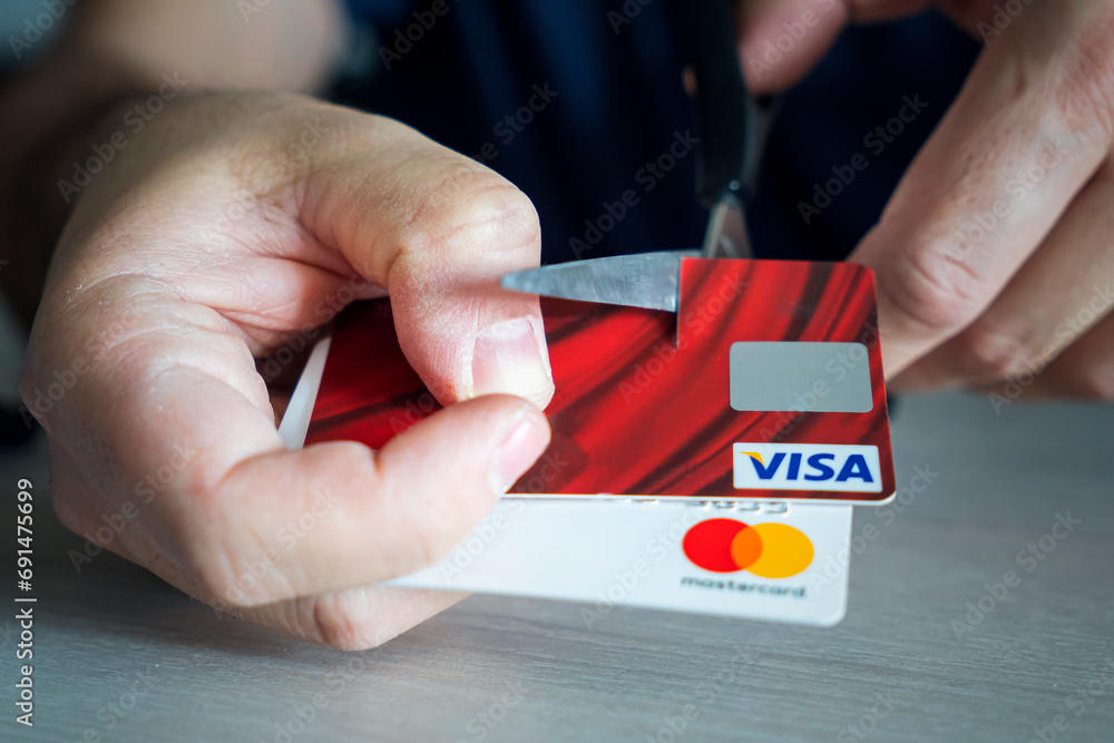a man cuts bank credit cards of the type and mastercard with scissors ...
