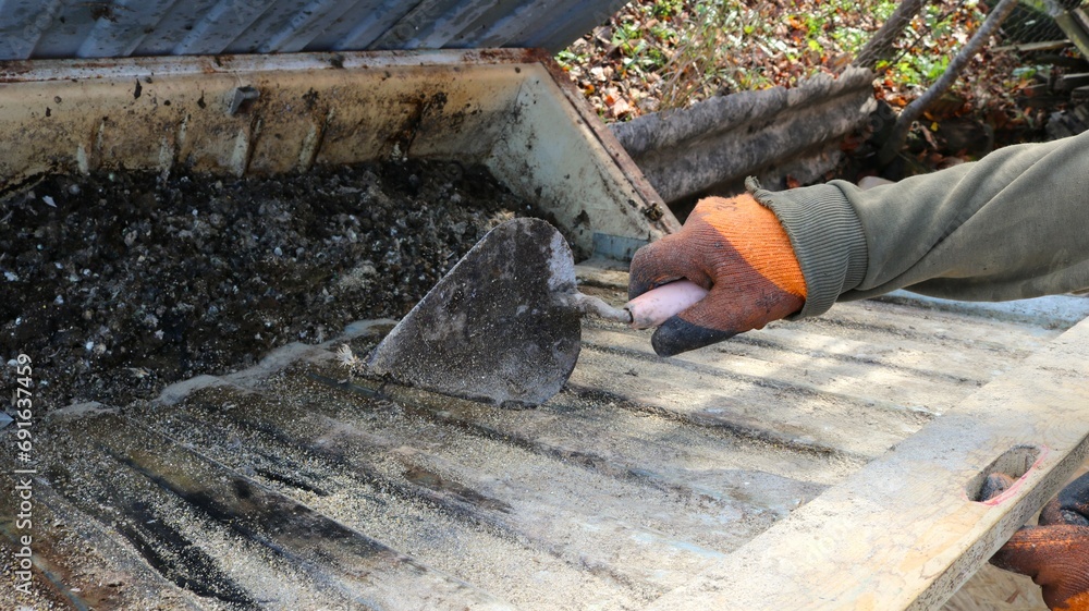 worker's hands use a metal scraper to scrape bird droppings from an ...