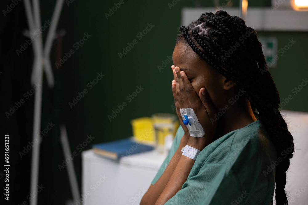 African woman sitting on a hospital bed, crying, and praying. Stock ...