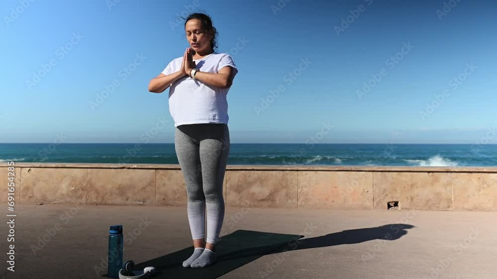 Active peaceful woman in sportswear, doing Surya Namaskar on yoga mat ...