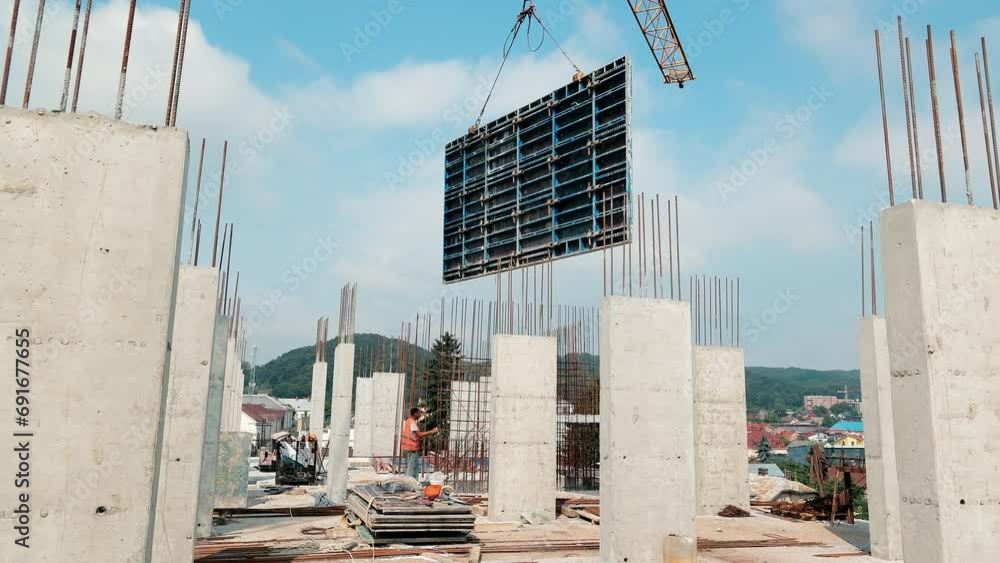 Construction of a multi-story building, a crane has lifted a large slab ...