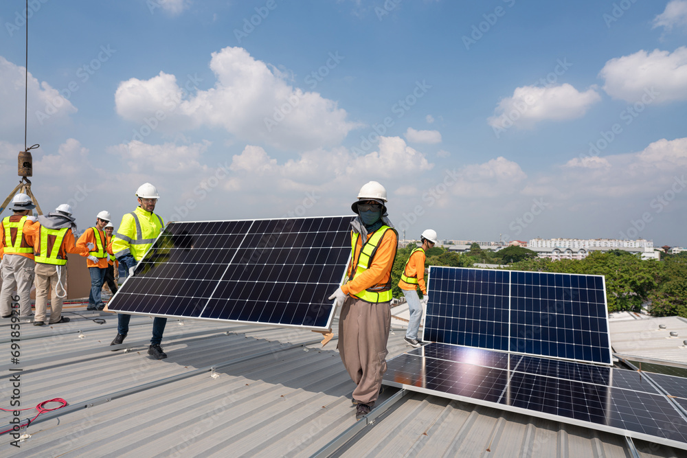 Men technicians carrying photovoltaic solar moduls on roof of factory ...