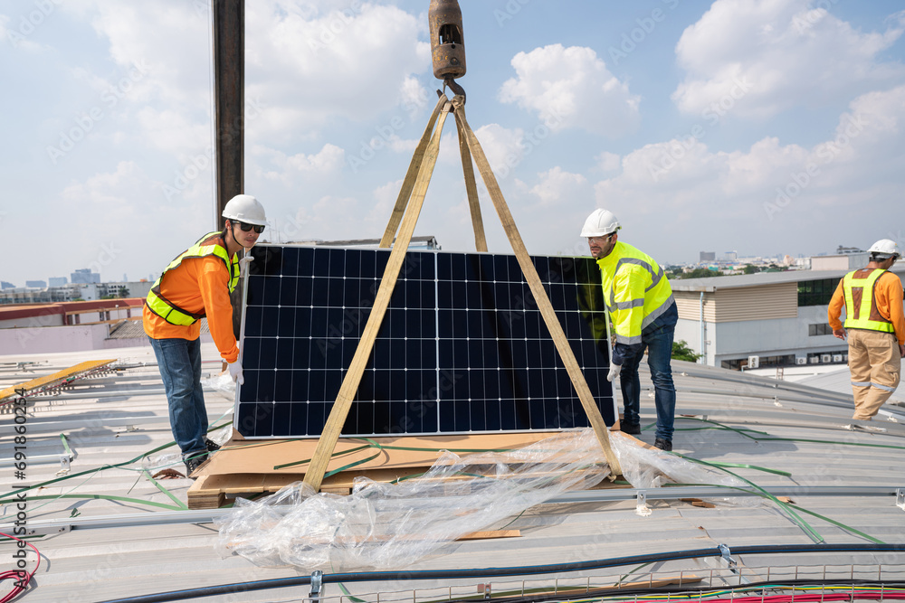 Men technicians carrying photovoltaic solar moduls on roof of factory ...