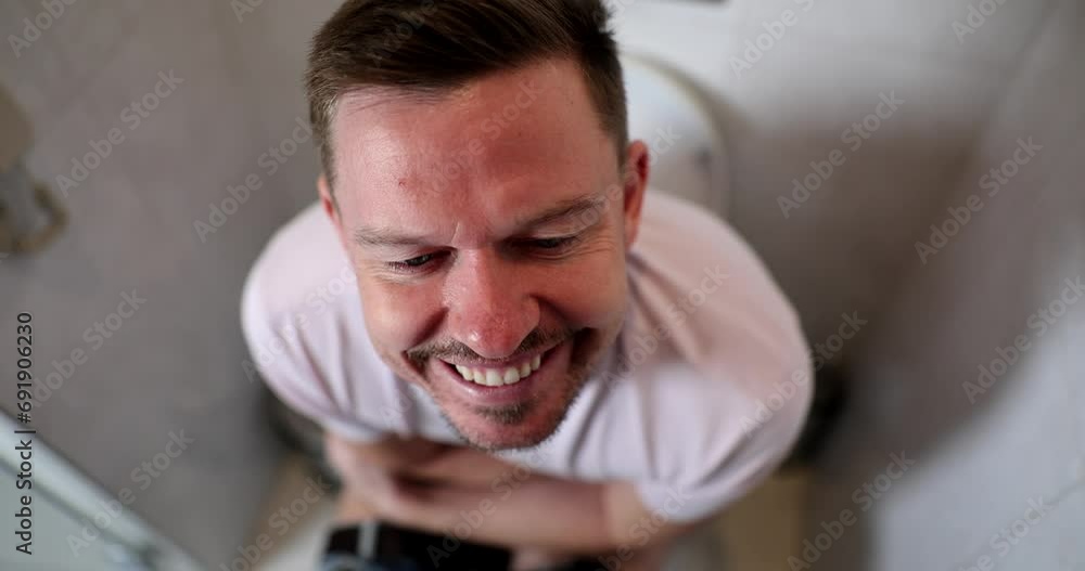 Sad man sits on toilet with bowel problems and smiles closeup ...
