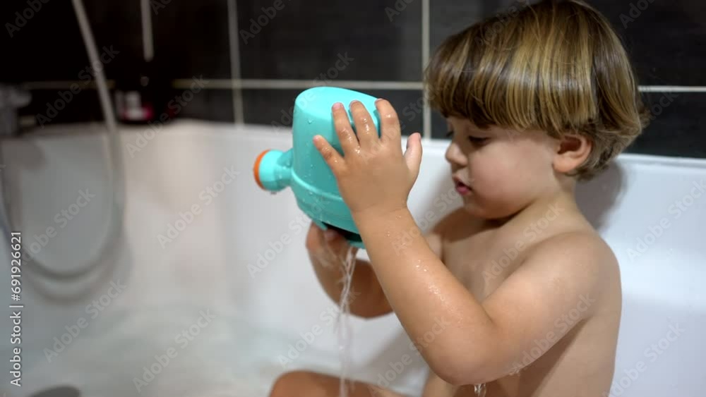 Little boy inside bathtub playing with plastic toy object, one male ...