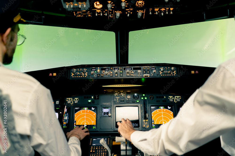 rear view of pilots in the cockpit of an airplane during flight control ...