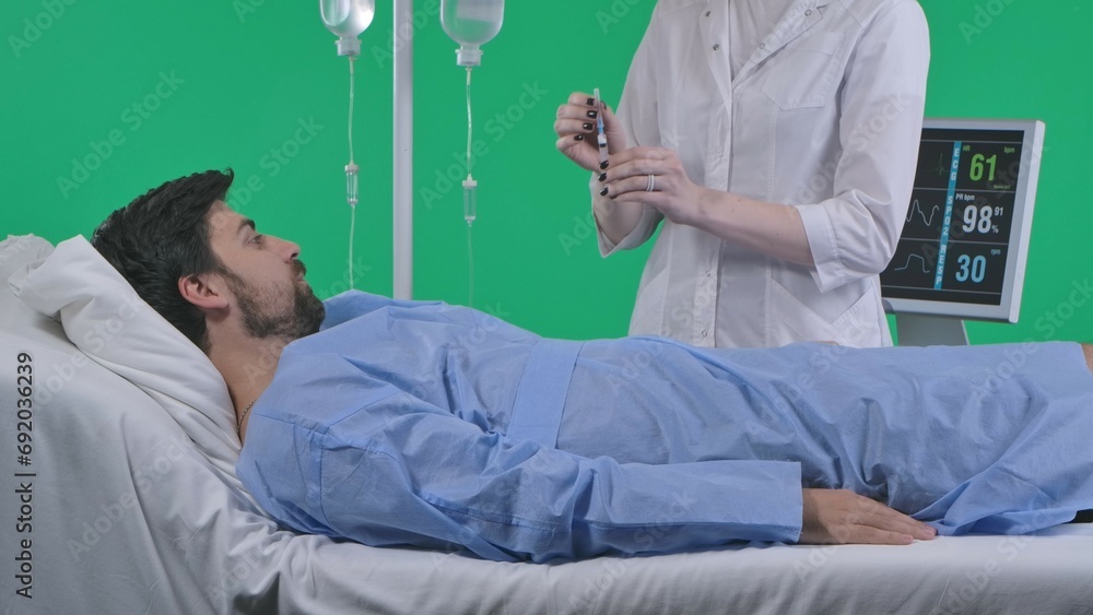 Adult man patient laying in bed with drip and monitor, female nurse ...