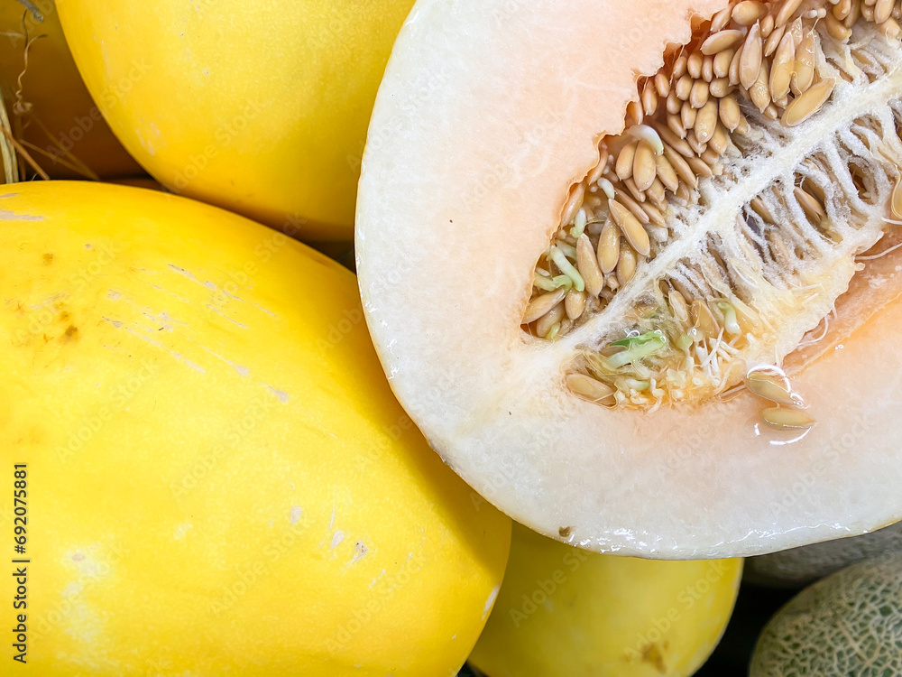 Half sliced fresh canary melons with yellow skin and orange flesh in ...