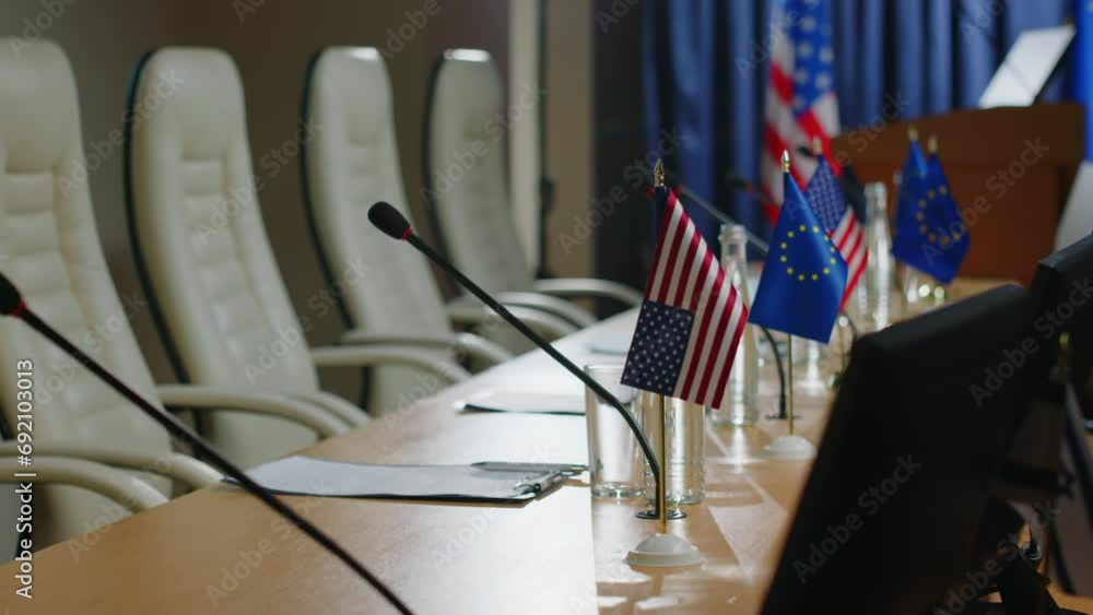 Press conference table with mics, water, monitors and national flags ...
