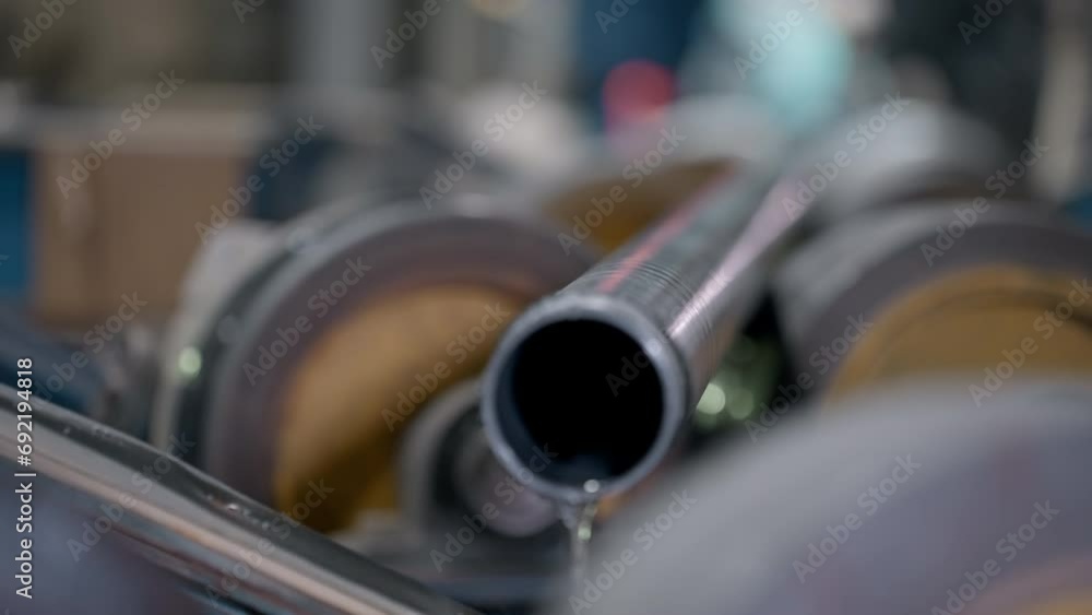 Steel pipe going through a rotating machine mechanism on the conveyor ...