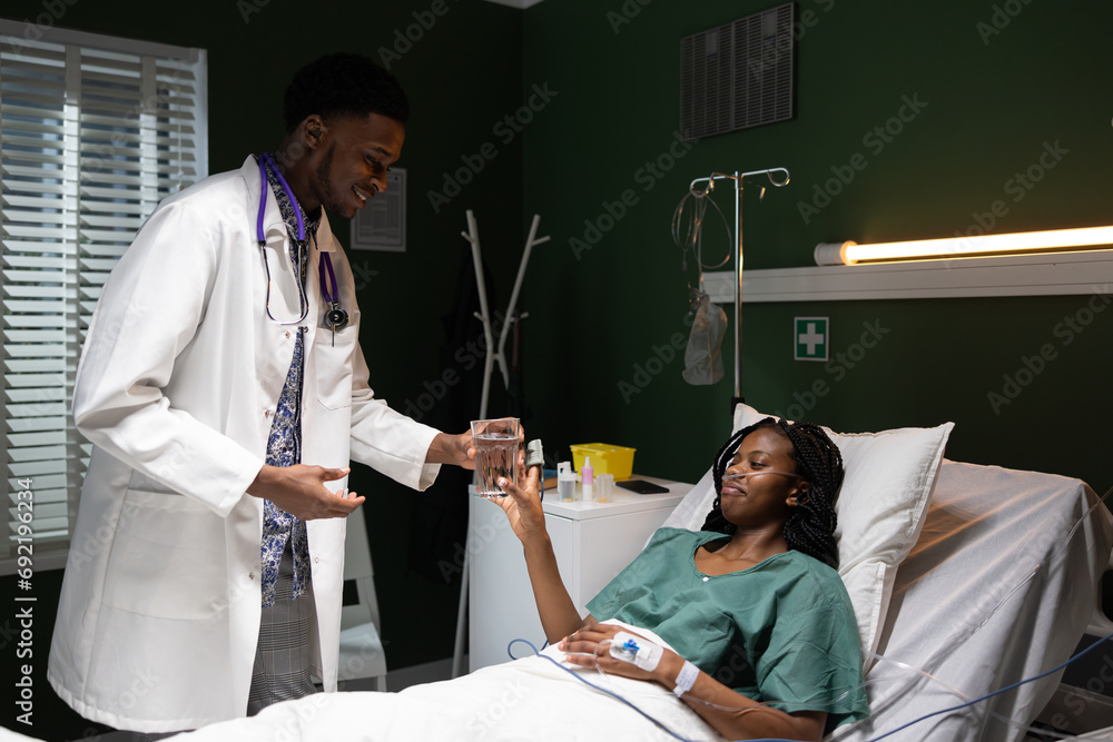 African doctor helps African patient in hospital gives her a glass of ...