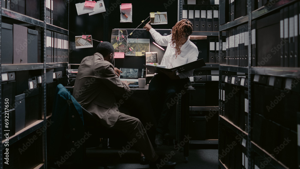 Two police officers examining case files reports, working on criminal ...