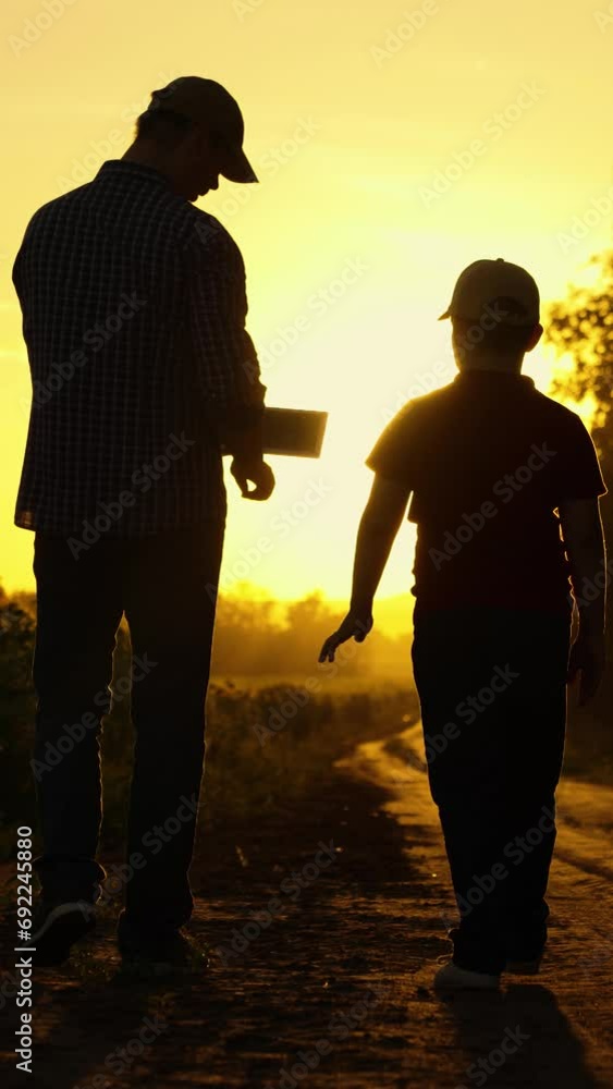 Dad teaches son how to farm. Farmer father walks with his son in ...