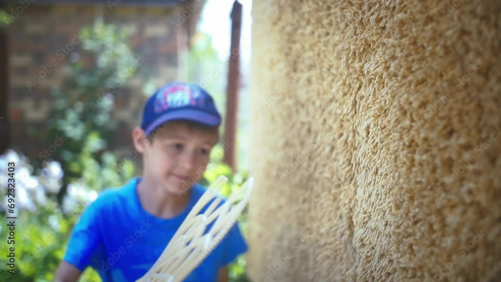 Energetic Outdoor Chores: Young Boy Vigorously Beating a Rug Outside ...