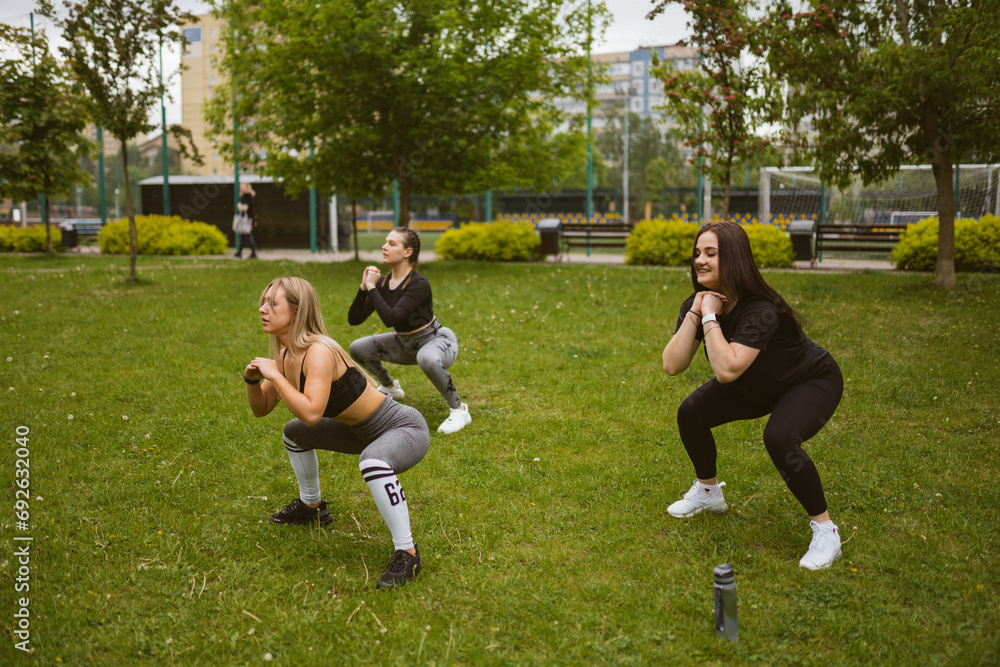 Foto de Sportswomen do squats together to pump gluteal muscles standing ...