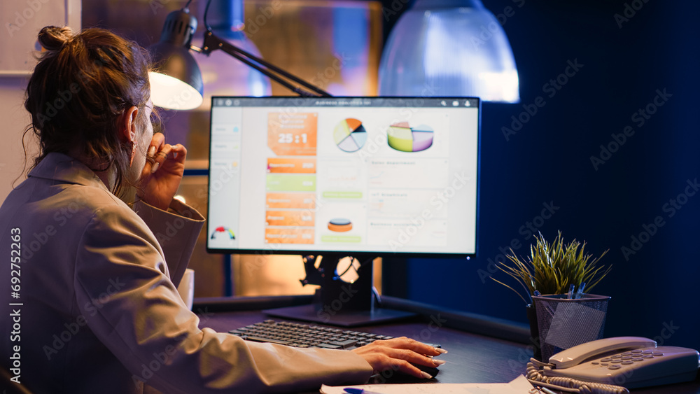 Office worker looking at computer running diagrams on screen, planning ...