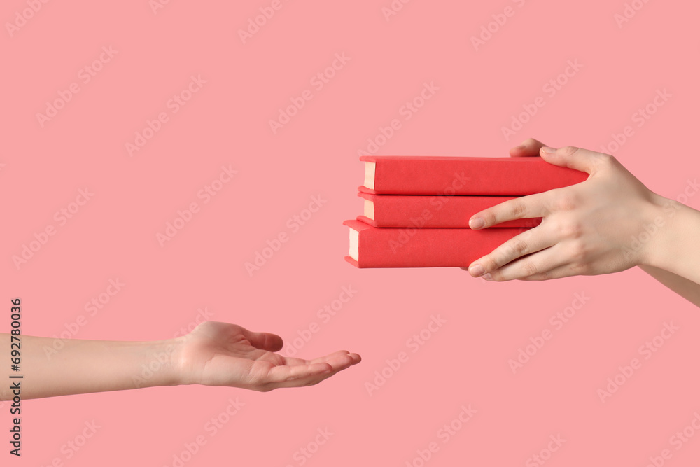 Hands passing stack of books to another person on pink background Stock ...