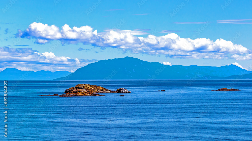 Rocky Island on the background of mountain range in the Strait of ...