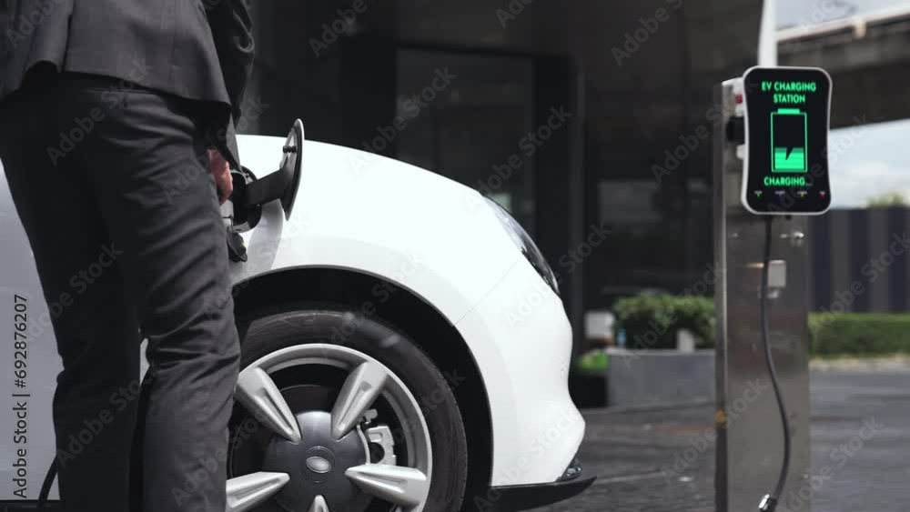 Businessman pull out EV charger from electric car from charging station ...