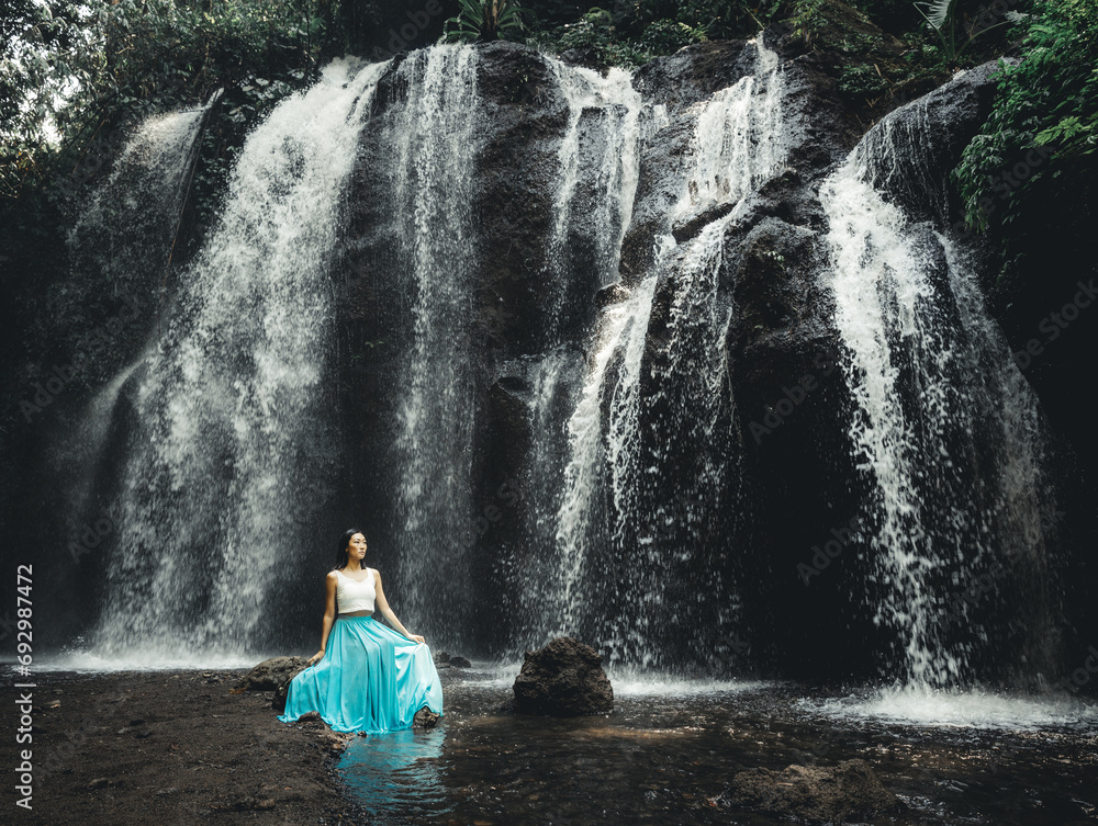 Young Asian woman sitting near waterfall. Nature and environment ...
