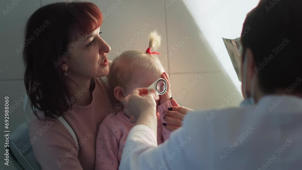 Pediatric ophthalmologist optometrist looks at eyes, checks vision of ...
