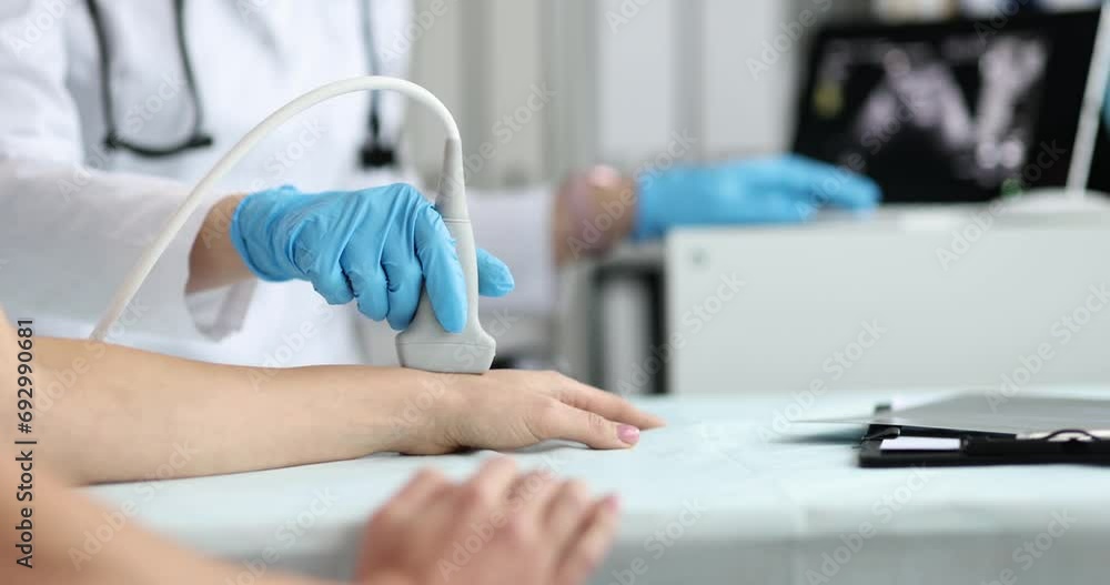 A woman doctor makes an ultrasound of the joints of her hand, close-up ...