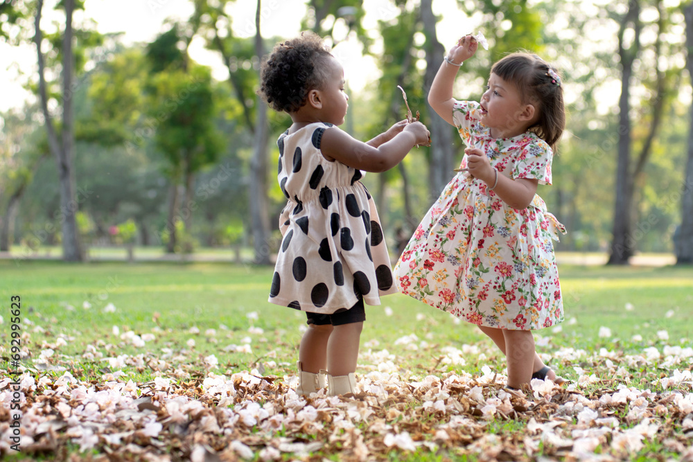 Two cute little girls with different skin colors playing at the park ...