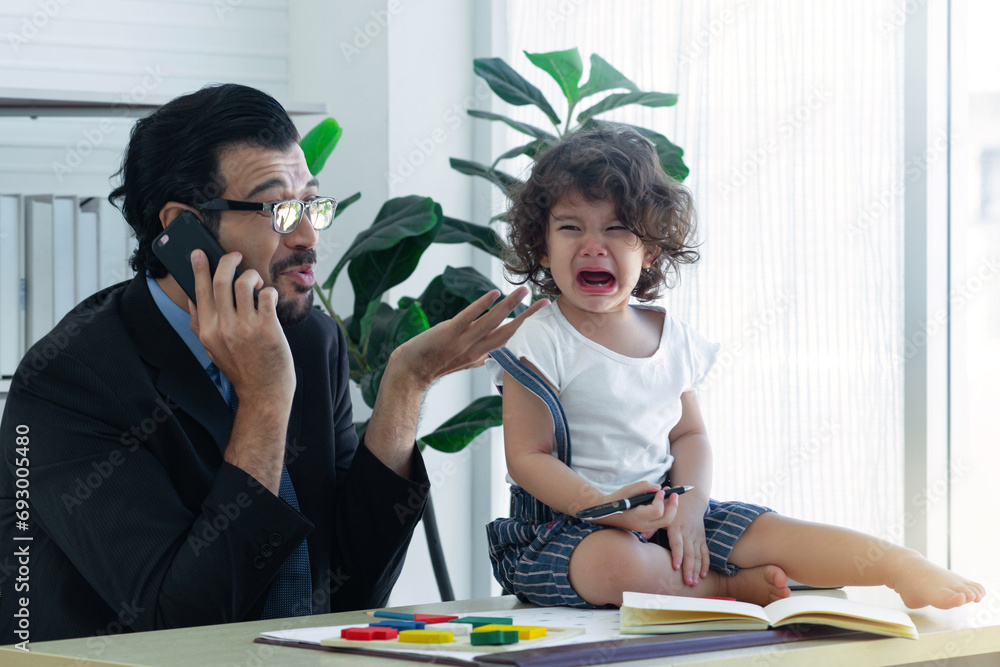 Dad is busy using his mobile phone to talk to someone, cute little girl ...