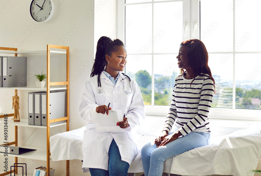 Happy African American female doctor and patient discussing treatment ...