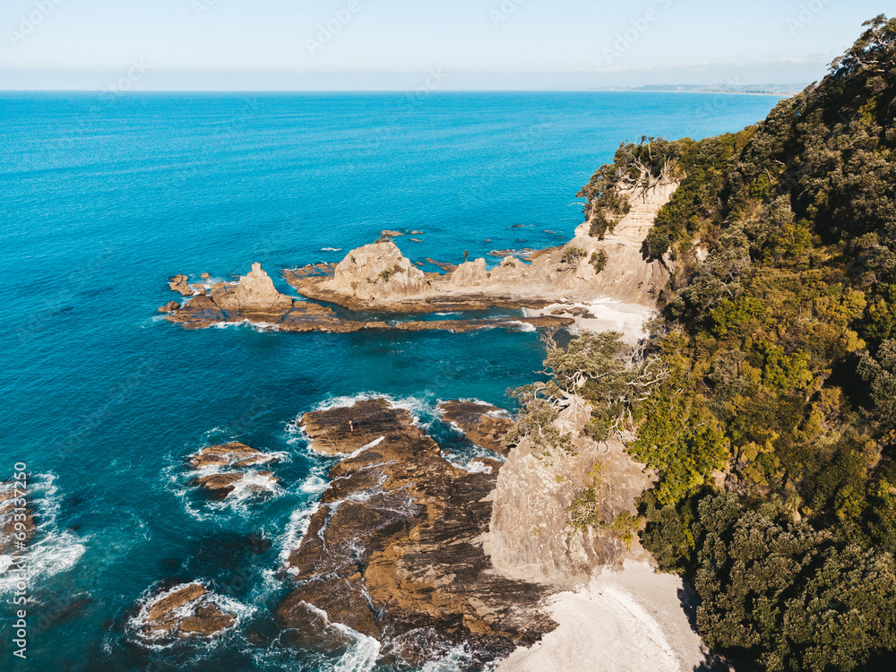 Drone photo above Ohope beach in New Zealand showing beaches, different rock formations, flora ...