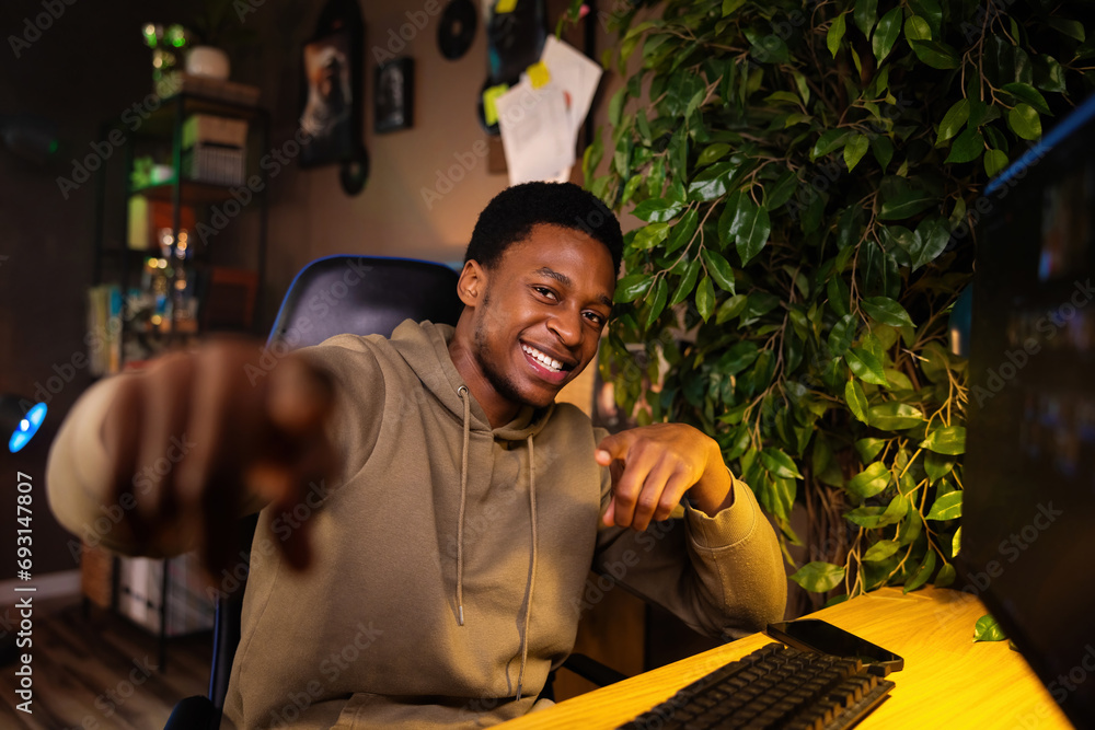 Delighted African man in living room points finger at camera signifying ...