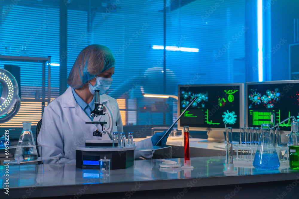 Female scientist sitting in a research lab with test tubes and flasks ...