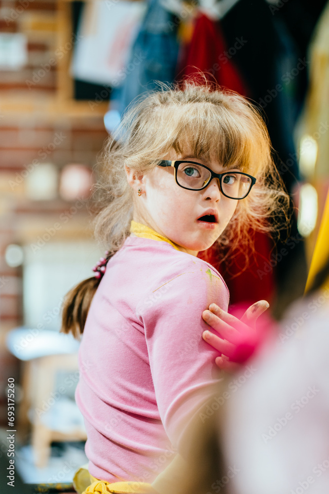 Vertical portrait of cute little girl with down syndrome painting in ...