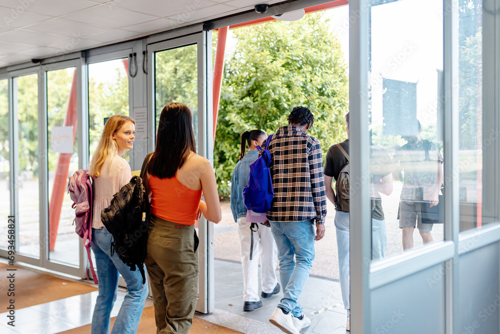 multiracial group of students leaving the school building, college ...