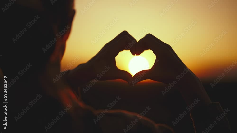 Woman folding hands at sunset in heart shape, symbol of real romantic ...