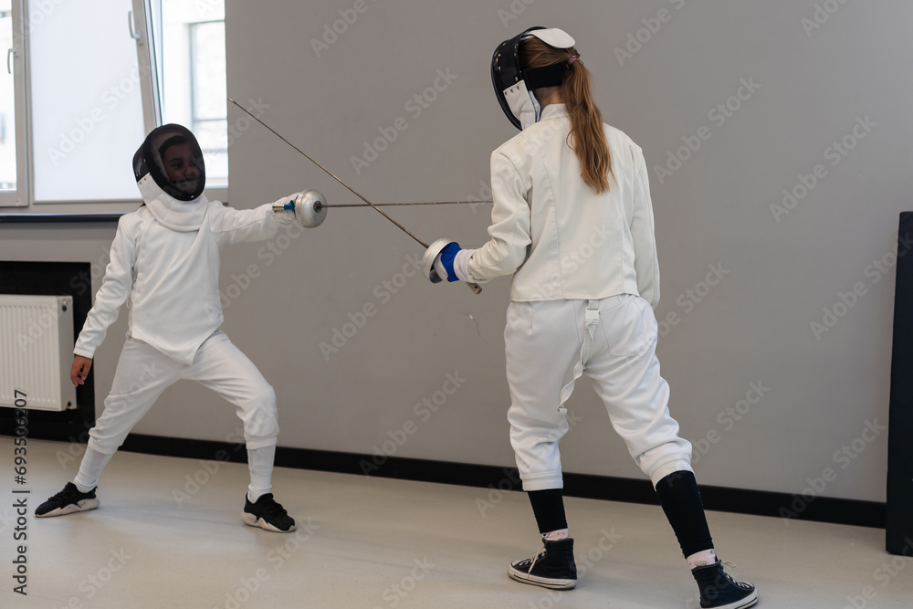 Adults and teens wearing a fencing uniform practicing with foil in the ...