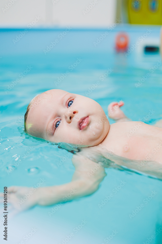Teaching children to swim. A baby learns to swim in a pool with a ...