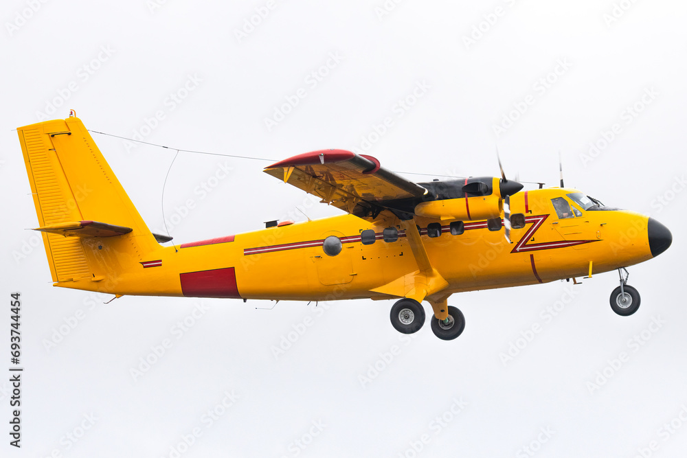 Bright yellow twin engine aircraft flying by. High wing airplane with ...