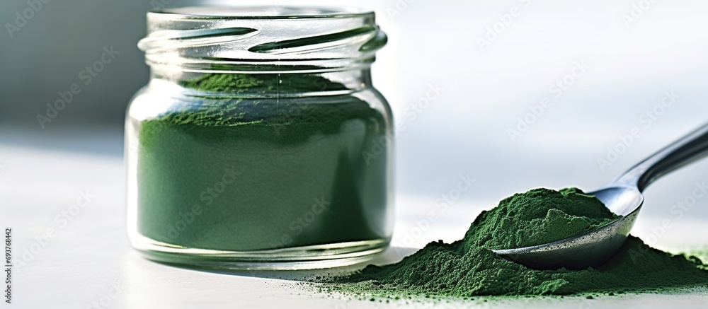 Organic blue-green algae spirulina powder food in glass jar with wooden ...