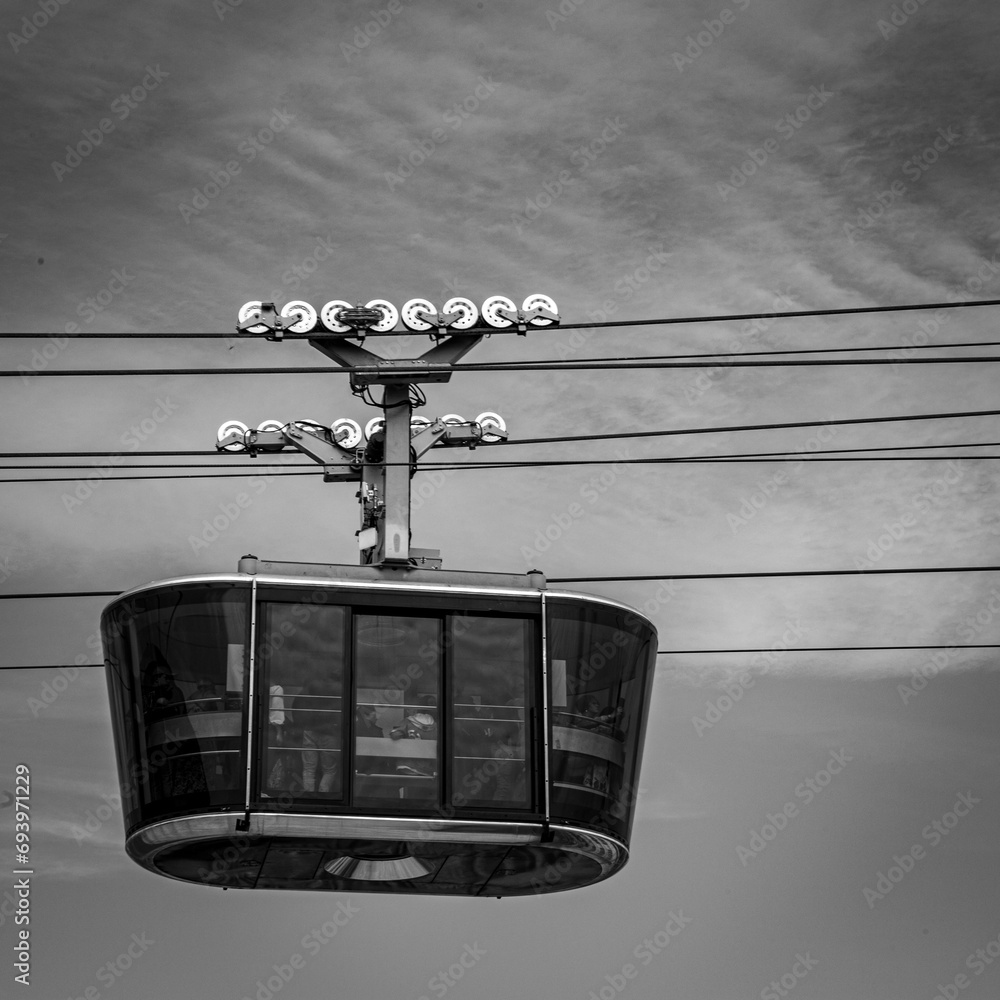 Cable car transporting people with sky and cables in black and white bw ...