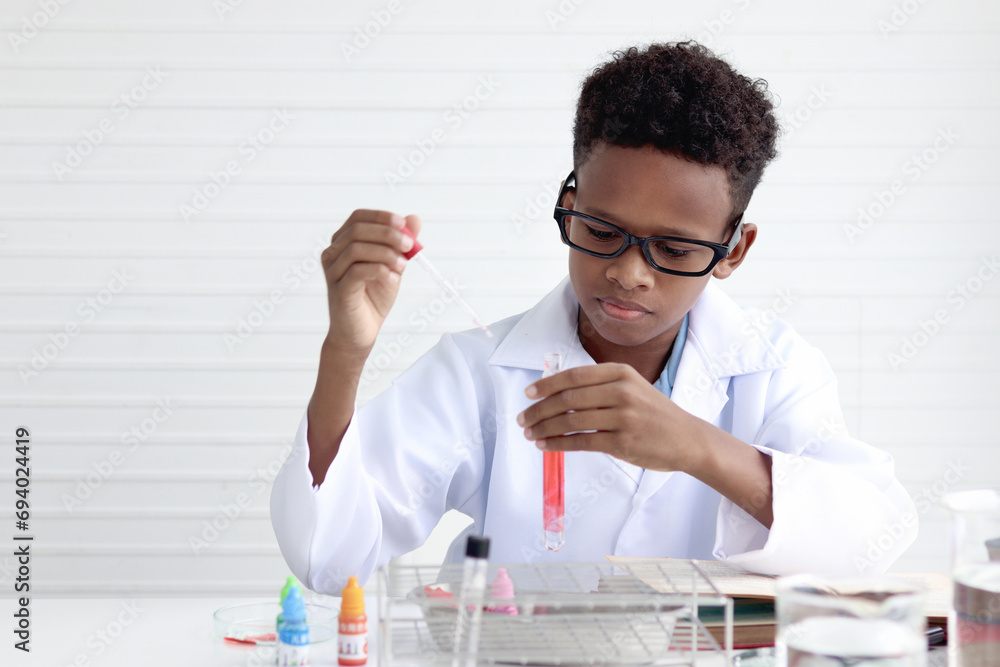 Foto de Concentrate African boy in lab coat holding a test tube for ...