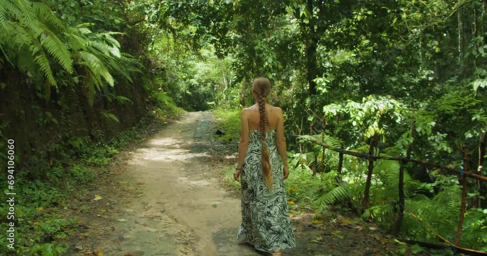 Young woman walking along forest path in jungle. Girl goes down to ...