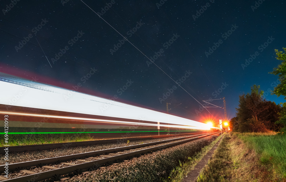 Light trails of a fast driving train at night with the stars of the ...