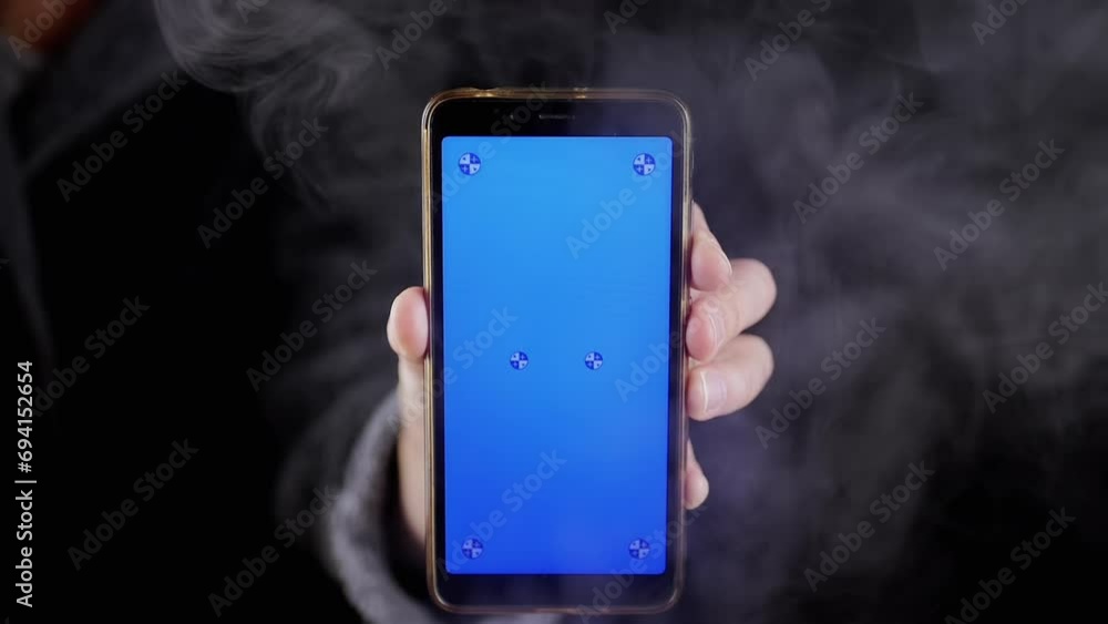 Hand Holding a Mobile Phone with a Blue Screen on a Black Background in ...