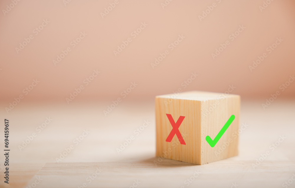 Decision-making concept portrayed by wooden block's green check mark ...