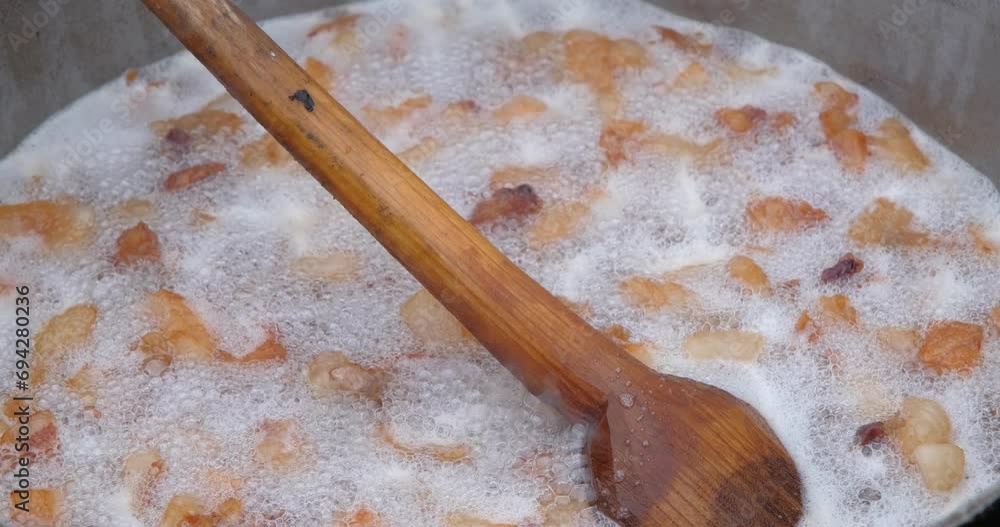 Preparation of delicious unhealthy fried pork greaves in a cauldron on ...